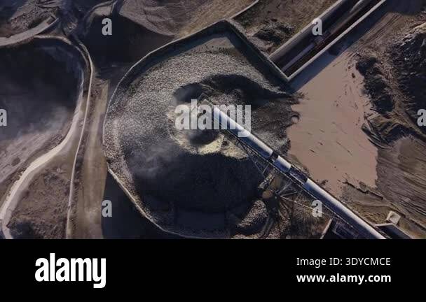 Aerial view shows quarry activity. Machinery transports materials from ...