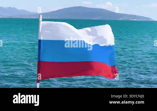 National flag of russia fluttering against a blue sea and mountains on ...