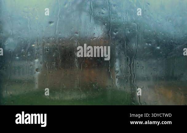 Streaming rain droplets on glass window during wet weather, sliding ...