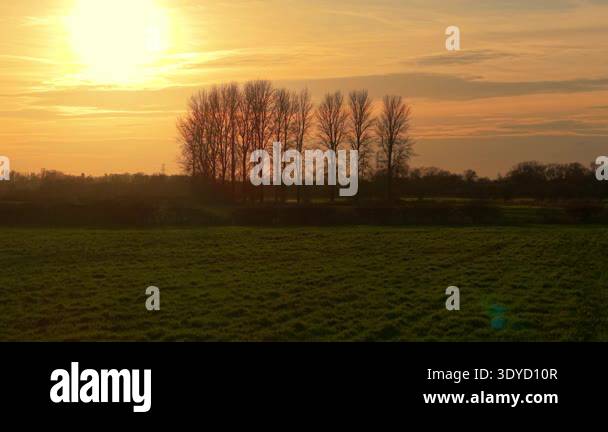 Golden sunset spreading across countryside farmland, warm evening sky ...