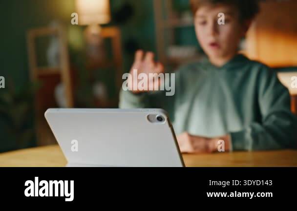 Schoolboy greeting tablet web camera starting video call sitting home ...