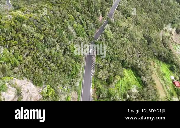 Aerial view of a gray car navigating a winding mountain road surrounded ...