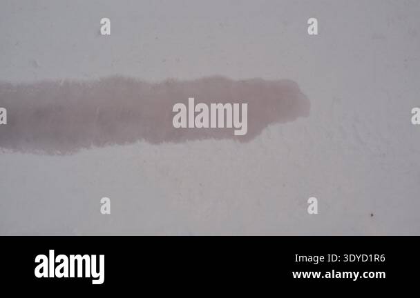 Abstract view of melting snow with dark, winding channels of meltwater ...