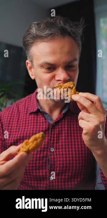 Caucasian man holding, biting and chewing fried chicken leg and french ...