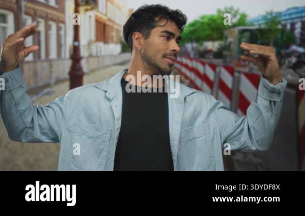 Young hispanic man uses hand gestures while speaking on street ...