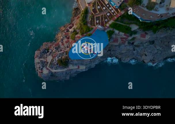 Blue helipad above ocean rocks holding a red helicopter Stock Video ...