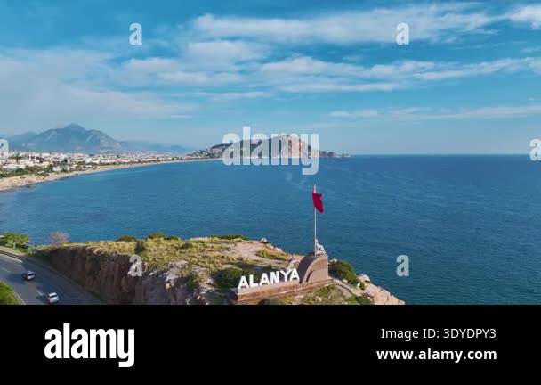 Drone captures Alanya sign and flag on rocky cliff with sea, beach and ...