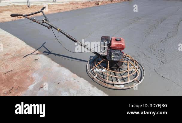 close up of a power trowel machine finishing fresh wet concrete on a ...