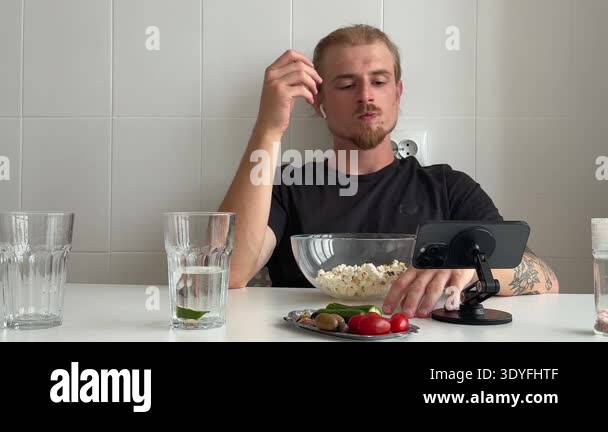 Caucasian male testing cucumber slice at kitchen table, picking fresh ...