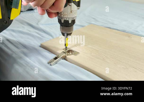 Man carpenter repairman unscrews bolts from cabinet door with tool ...