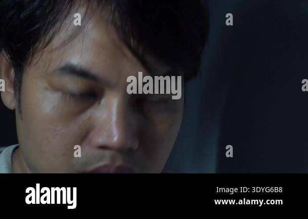 Close-up of a depressed Asian man with a sad and weary expression ...