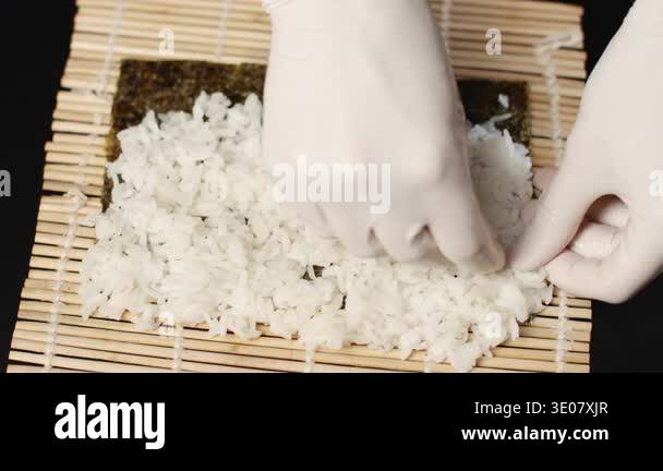 Talented sushi chefs hands wearing white gloves carefully spreading ...