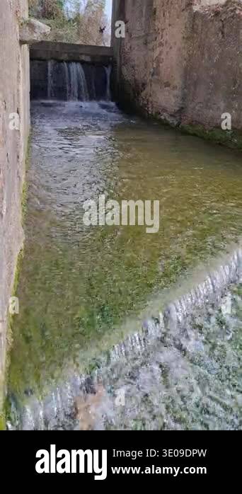 Historic stone water channel with moving clear stream and small cascade ...