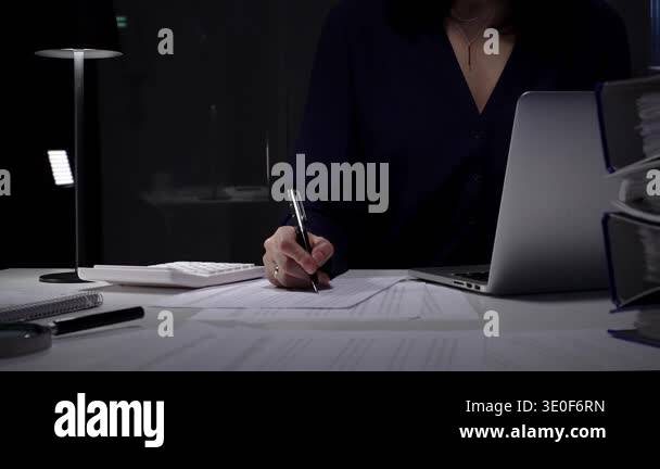 Womans hand writing with a pen on paper, working late at night in an ...