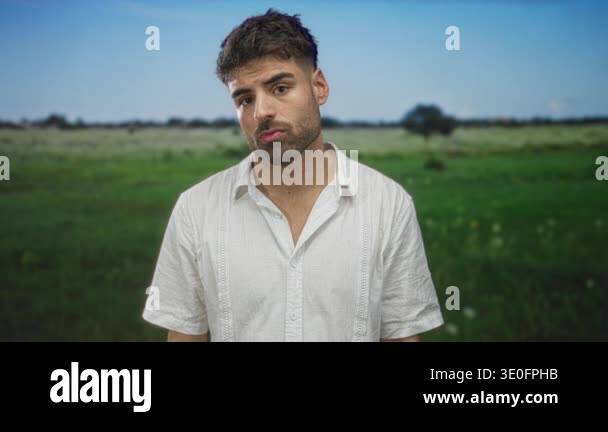 Man pursing lips in forest clearing under blue sky and green meadow in ...