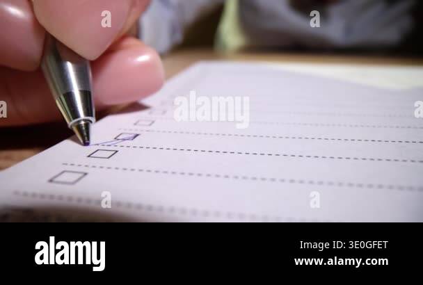 Closeup of hand putting checkmark or marking with blue pen on checklist ...