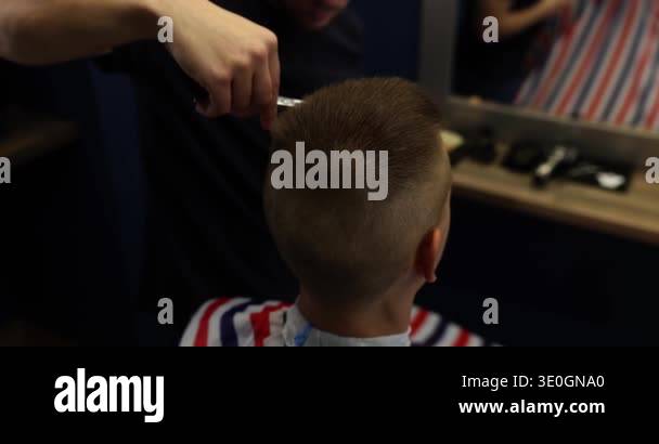 Hairdresser carefully trims hair in temporal area of man client head ...