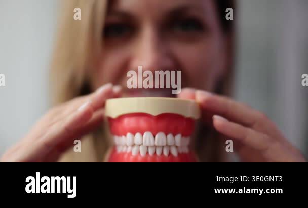 Woman holds artificial jaw and smiles. Ideal and beautiful shape of ...