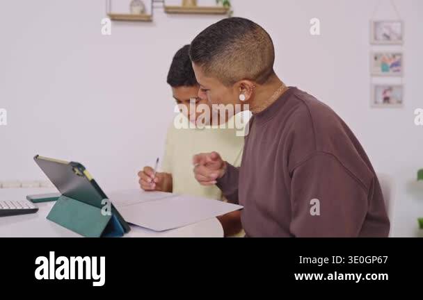 Supportive latin mother tutoring her son at home. Focused boy writing ...