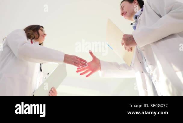 Two doctors meet, shake hands and discuss patient medical history ...