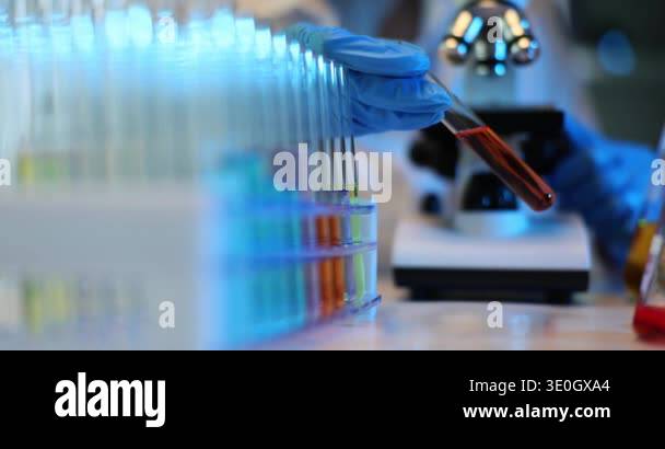 Scientist mixing chemicals in a test tube with red liquid in laboratory ...