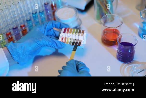 Scientist x holds a strip of litmus paper dipped in a purple liquid and ...