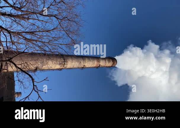 Single industrial smokestack releasing white smoke into blue sky ...