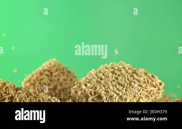 Instant noodles fly up and fall down on a green background. Filmed on a ...