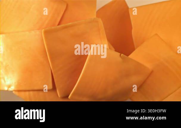 Slices of cheddar cheese fly and fall. Filmed on a high-speed camera at ...