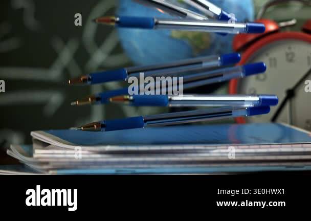 Pens fall on school notebooks. Filmed on a high-speed camera at 1000 ...