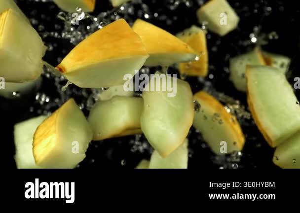 Pieces of melon fly on a black background. Filmed on a high-speed ...