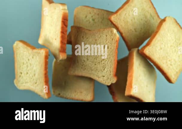 Pieces of bread fly up and fall on a blue background. Filmed on a high ...