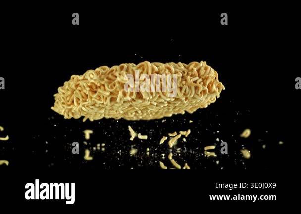 Dry instant noodles falling on a black background. Filmed on a high ...