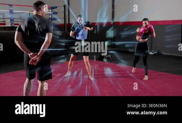 Coach stepping in while athletes sparring on red mat boxing drill ...