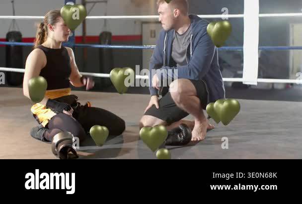 Female boxer sitting up after falling while coach checking in boxing ...