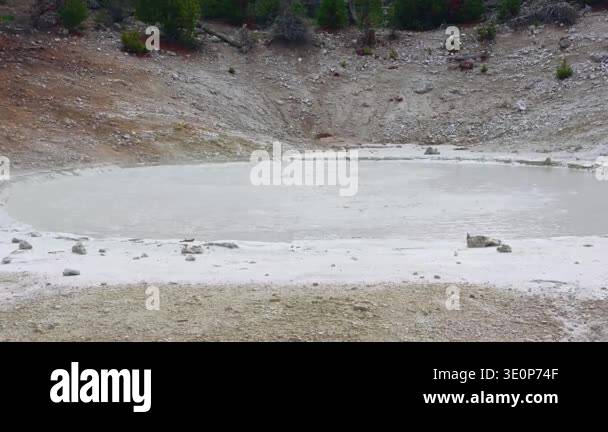 Bubbling thermal mud pot surrounded by white mineral deposits and ...