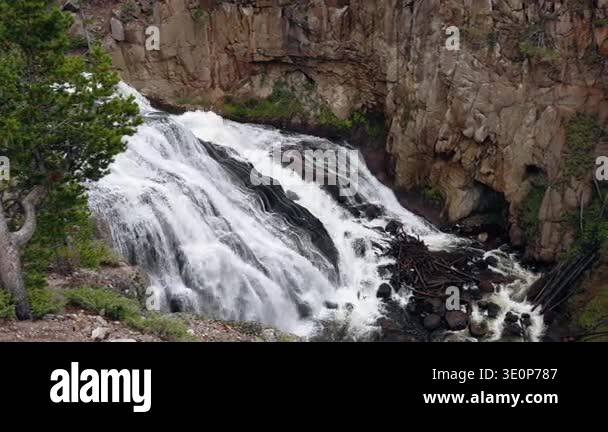 Powerful waterfall cascading and rushing through rocky canyon cliffs in ...