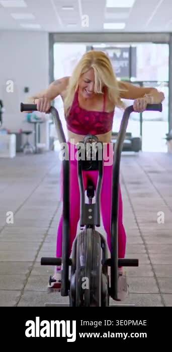 Fit woman performing a high intensity cardio workout using a fan bike ...