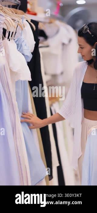 Young woman choosing clothes from a boutique rack, comparing soft ...