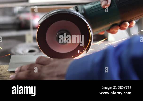 Close up of a worker cutting a metal plate using an electric angle ...