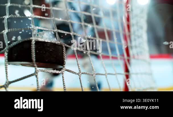 Super slow motion close-up of a hockey puck hitting the goal net as a ...