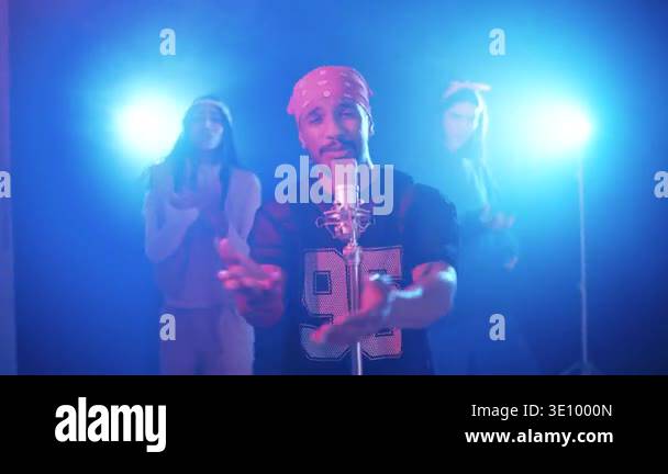 Rapper performing his reggaeton song in a studio with two female ...
