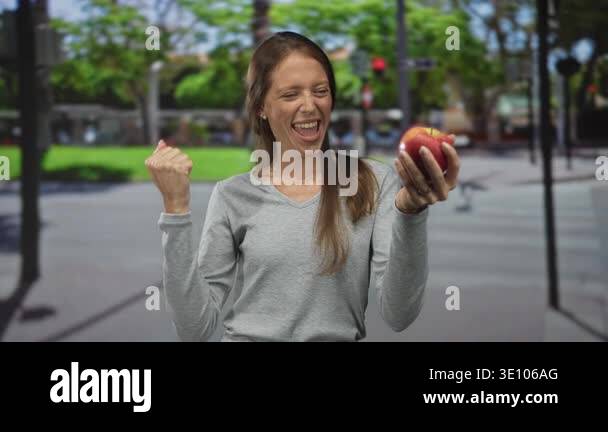 Woman holding red apple in open hand while pumping fist in a victory ...