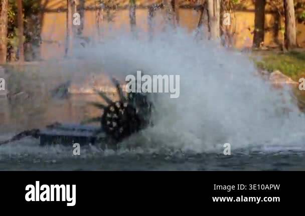 Water paddle wheel aerator splashing and spraying water in a pond ...