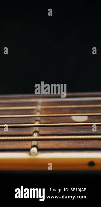 Acoustic guitar fretboard and strings are shown in a macro close-up ...
