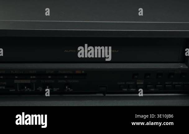 Male hand inserts black VHS cassette tape into vintage VCR player slot ...