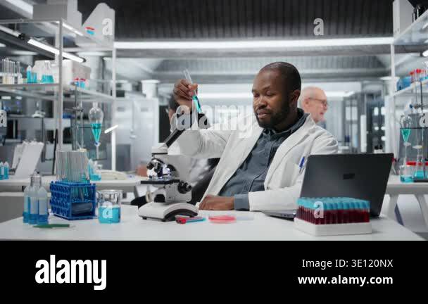 Portrait of smiling lab scientist investigating blue liquid polymer ...