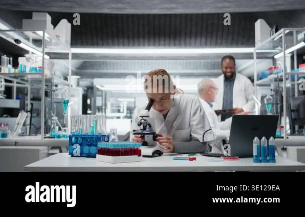 Clinical microbiologist using compound microscope for detailed cellular ...