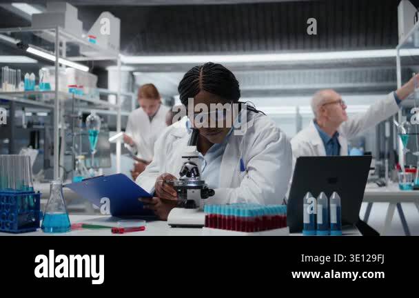 Female scientist using optical microscope to study microorganisms in ...