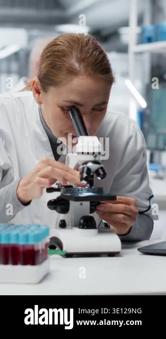 Vertical video Histology technician examining pathology slides under ...